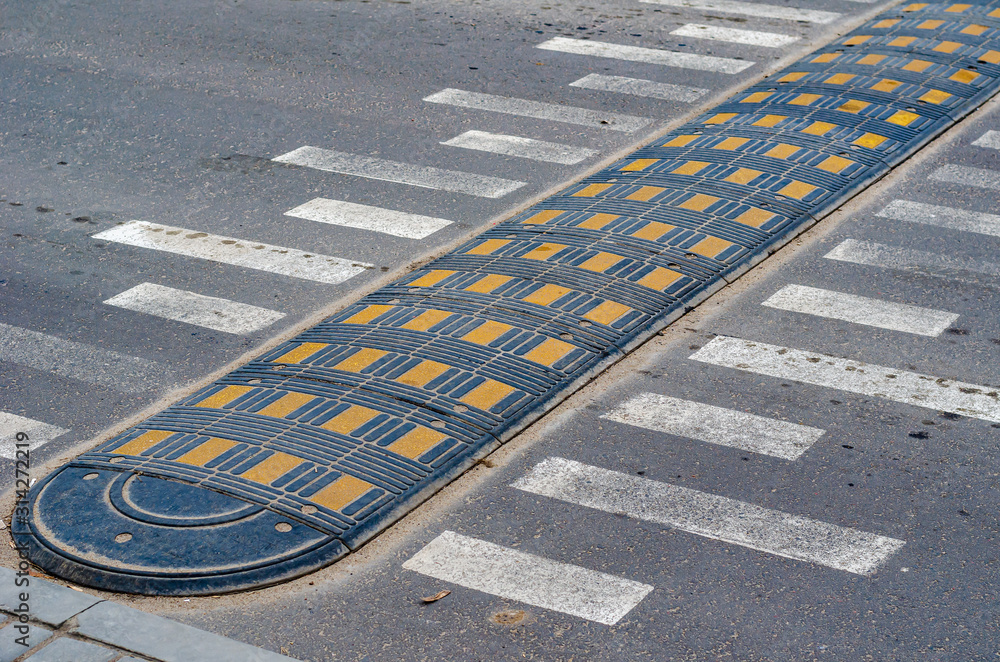 Speed bump on a city street. Speed bump and road markings on the ...