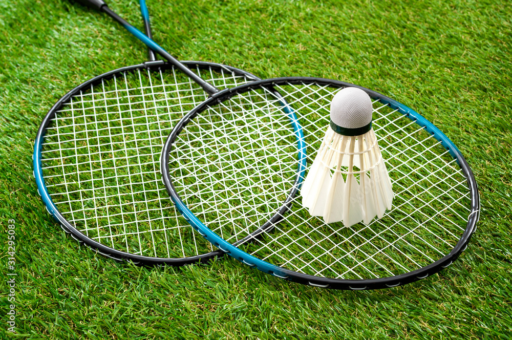 Photo Stock Summer picnic relaxing in the outdoors and leisure games played outside conceptual idea with shuttlecock made of feathers or shuttle and badminton racket on green grass background Adobe St...