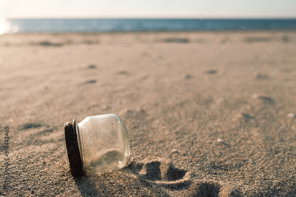 Glass container jar trash on sandy sea coast, polluted ecosystem ...
