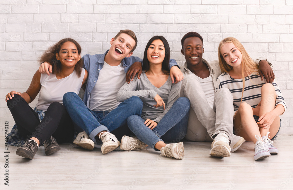 Students embracing and having fun over white brick wall Stock Photo ...