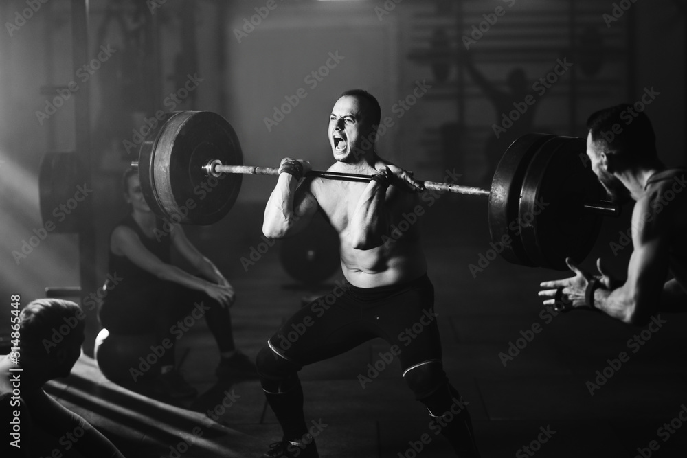 Muscular build man shouting while lifting barbell in health club. Stock ...