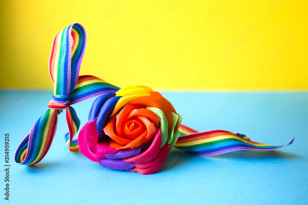 Artificial rose of rainbow color and a bow from a rainbow ribbon on a ...