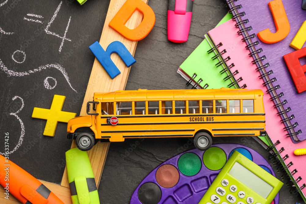 Flat lay composition with yellow school bus model on black background ...
