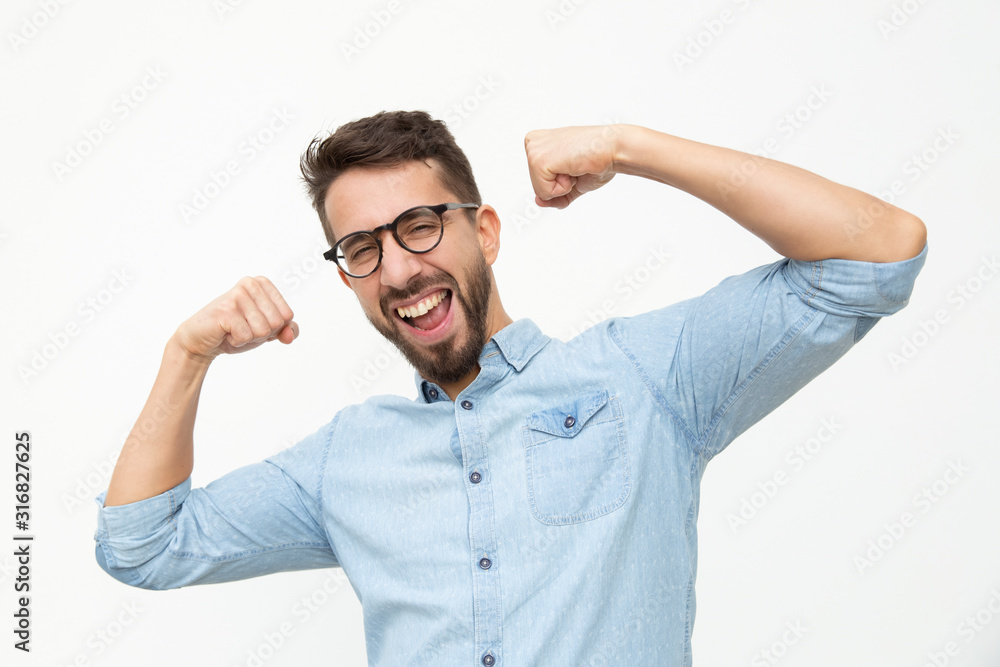 Excited young man showing biceps. Handsome happy young man in ...