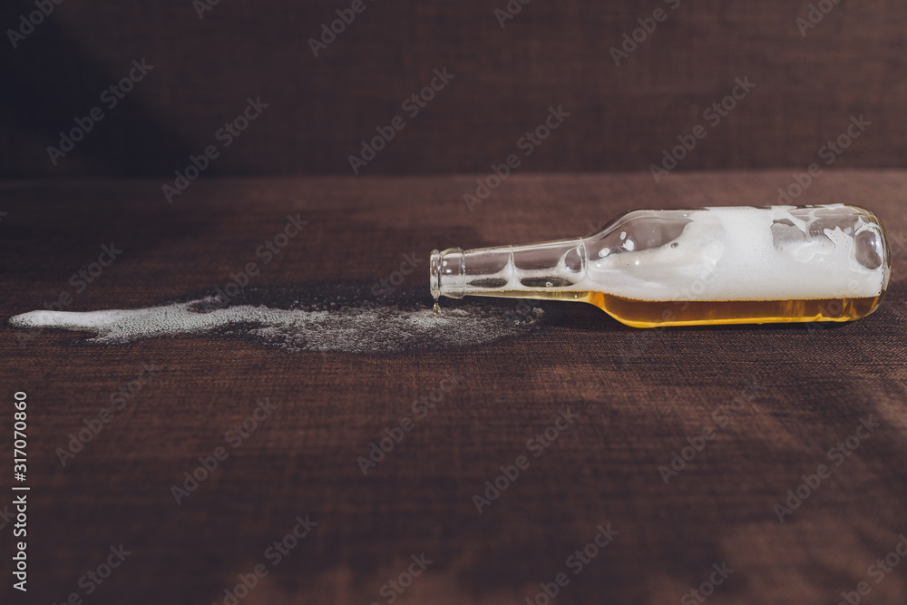 Alcoholism in the family. Beer bottle and spilled beer in the sofa ...