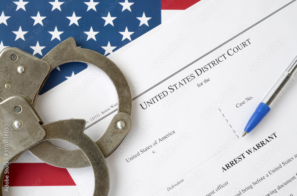 District Court Arrest Warrant court papers with handcuffs and blue pen ...