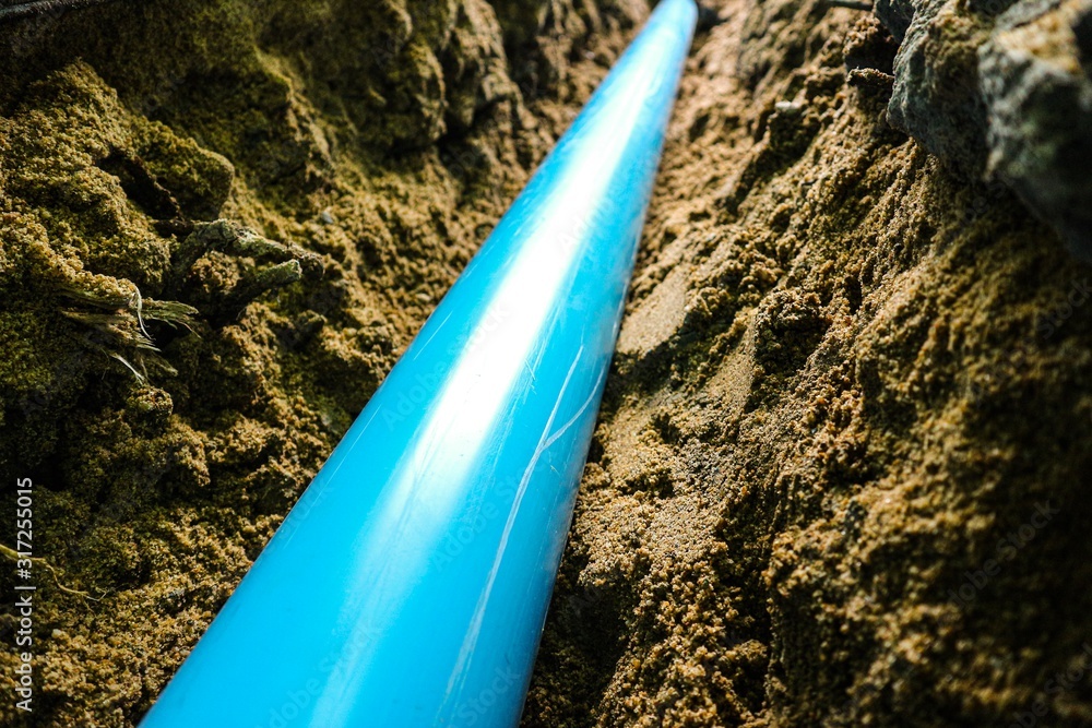 laying PVC water pipe under backfilling sand trench with dark ...