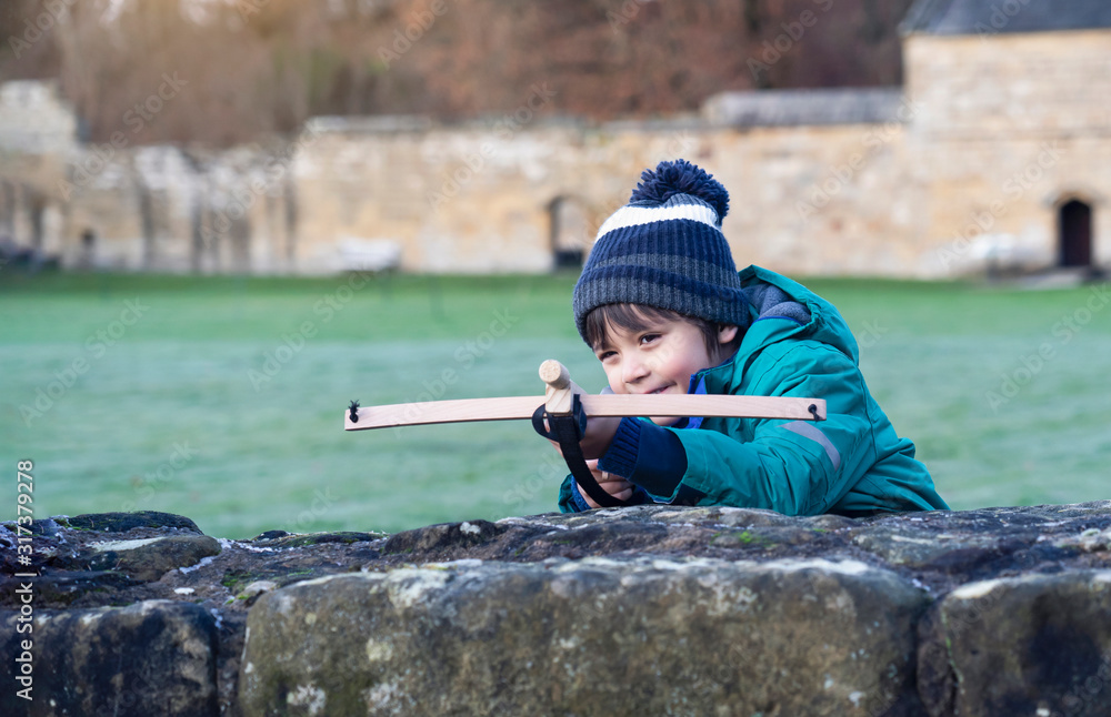 Portrait of happy kid with smiling face standing behind old wall ...