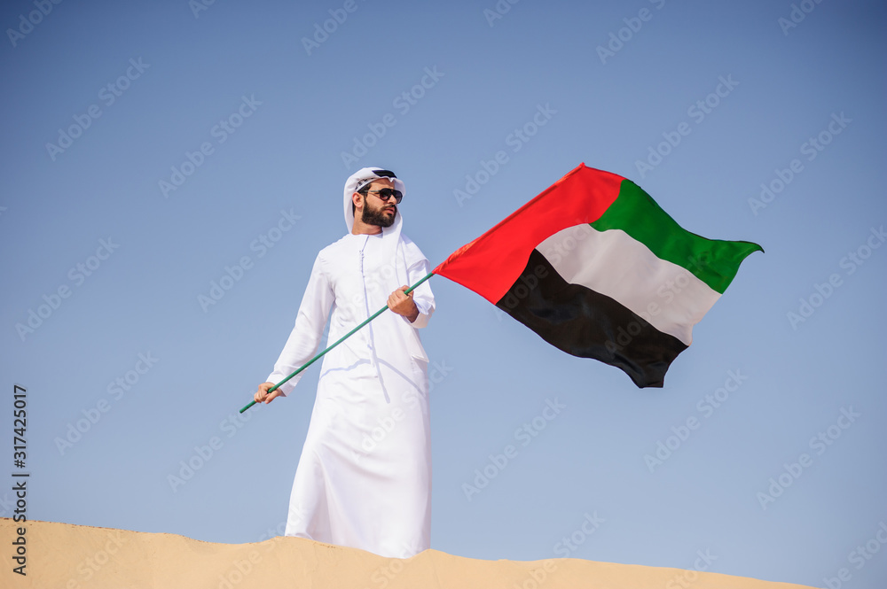 Proud arabian Emirati man holding a UAE flag in the desert. Stock Photo ...