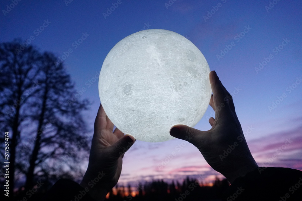 Round full moon in hands against evening sky. Lunar model, moon-shaped ...