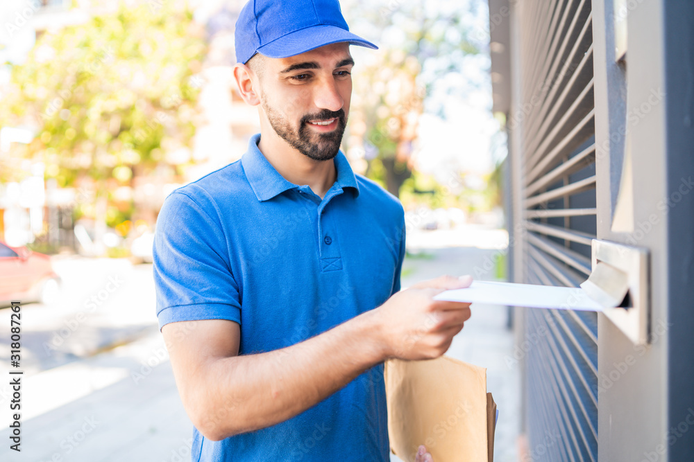 Postman putting letter in mailbox. Stock Photo | Adobe Stock