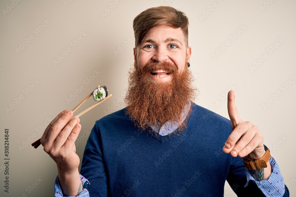 Redhead Irish man with beard eating green maki sushi using chopsticks ...