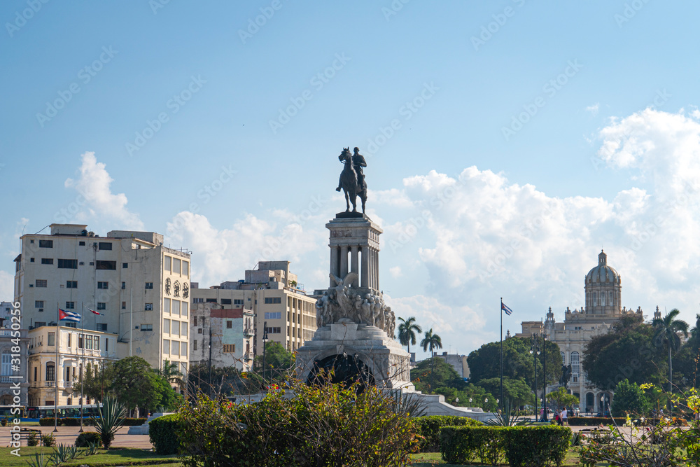 Statue of General Maximo Gomez against a blue cloudy sky. MAXIMO Gomez ...