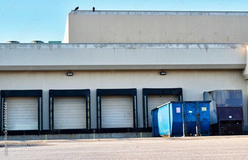 Four loading dock doors behind a commercial building with a blue ...