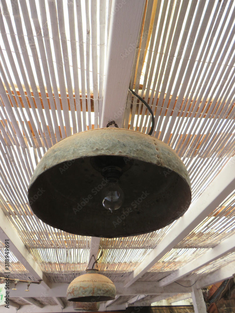 Perspective view of old wrought iron lamp on wooden beams in Caribbean ...