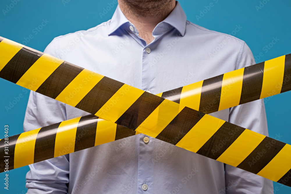 Man standing behind black and yellow lines of barrier tape that forbids ...