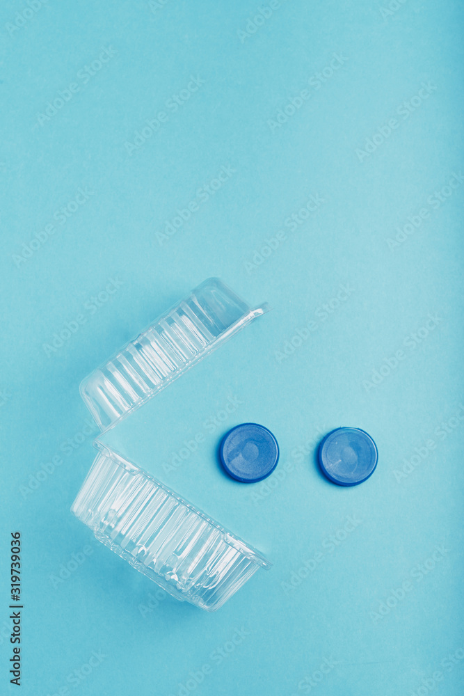 Plastic packaging and bottle caps over blue background. Collecting ...