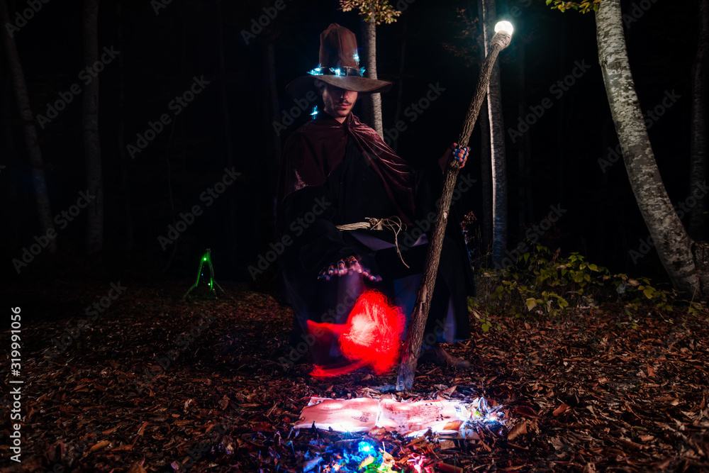 Wizard (mage) casting a spell with his magical staff while standing in ...