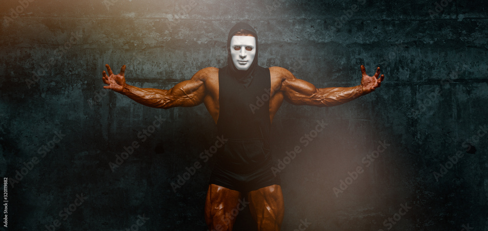 Foto de Stock Mysterious Muscular man hiding behind mask Flexing ...