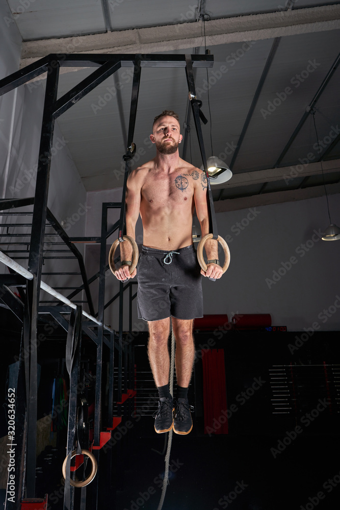 Strong man doing strength exercises on a bar in the gym with magnesium ...