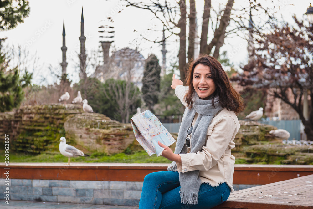 Beautiful young girl in fashionable clothes looks map and shows ...