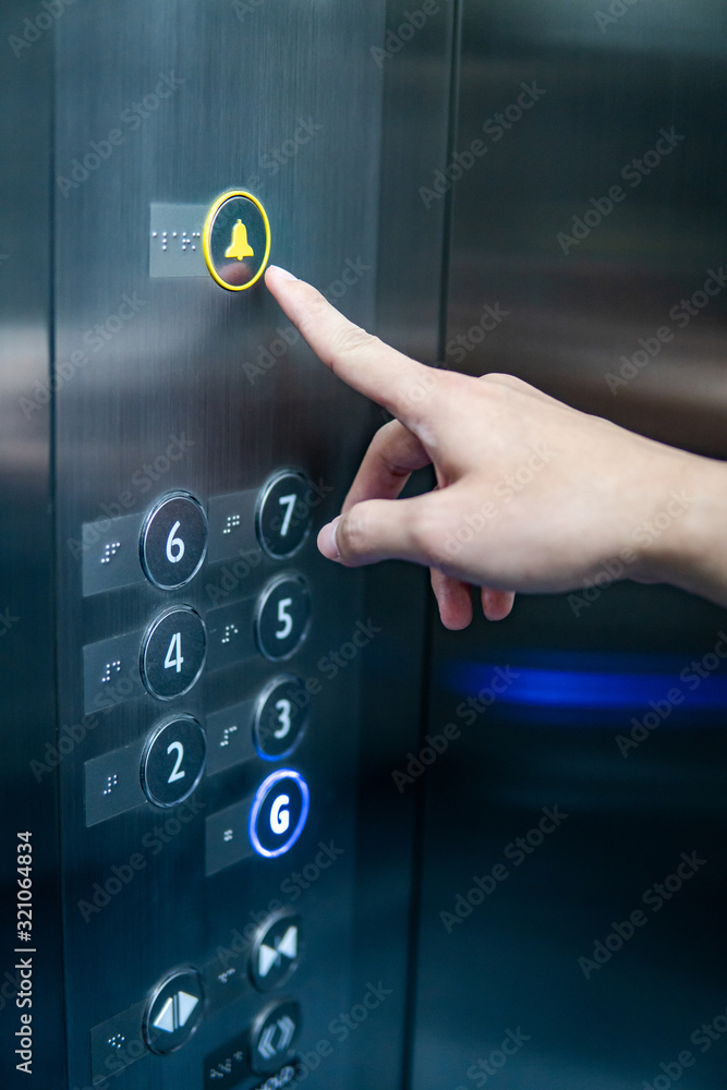 Male forefinger pressing on emergency stop and alarm button in elevator ...