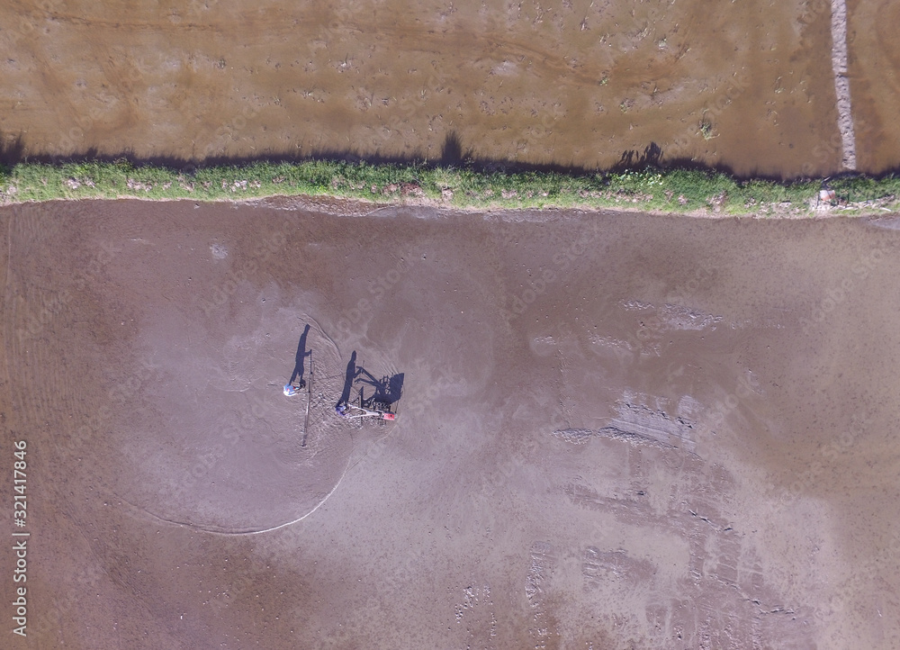 The shadow of two farmer using tractor to prepare the rice field for ...