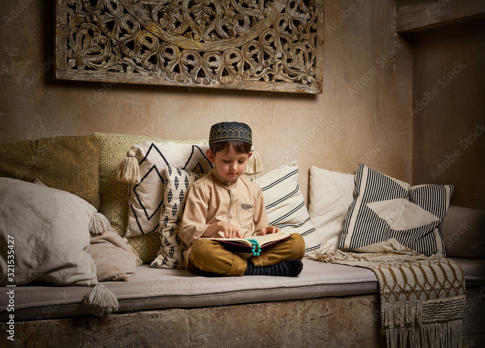 Zdjęcie bez tantiem: Muslim boy in prayer cap and arabic clothes with ...