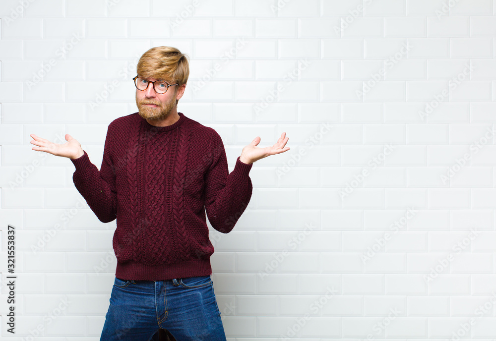 young blonde man feeling puzzled and confused, doubting, weighting or ...