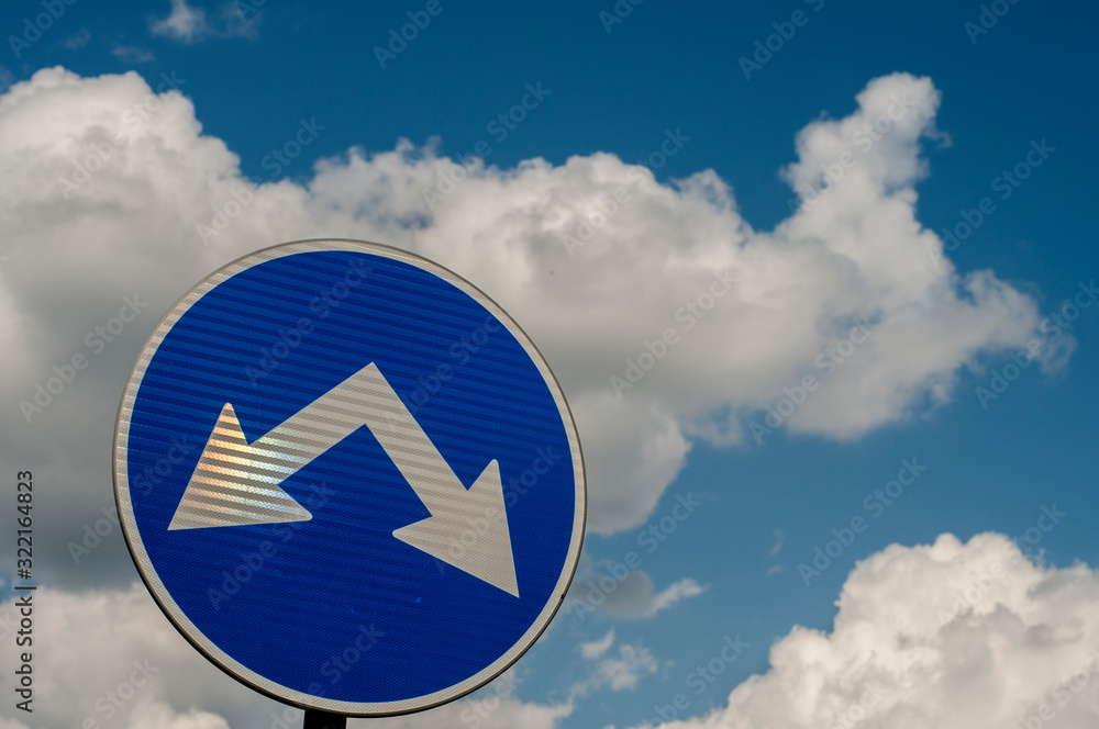 Blue traffic road sign with two arrows for two directions closeup on ...