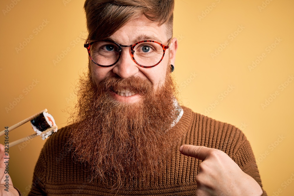 Redhead Irish man with beard eating salmon maki sushi using chopsticks ...