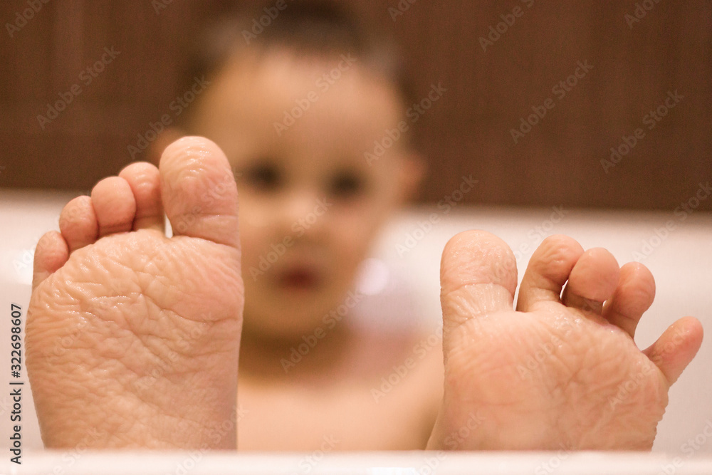 Wrinkled bare feet coming out from a bathtub. Child getting a bath feet ...