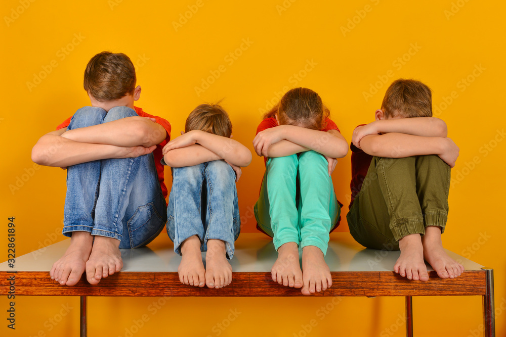 Foto Barefoot children sit with their legs crossed and hugging their ...
