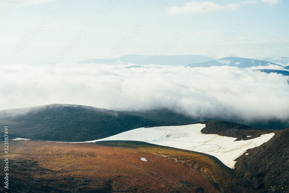 Atmospheric alpine landscape with giant low cloud above rocky mountain ...