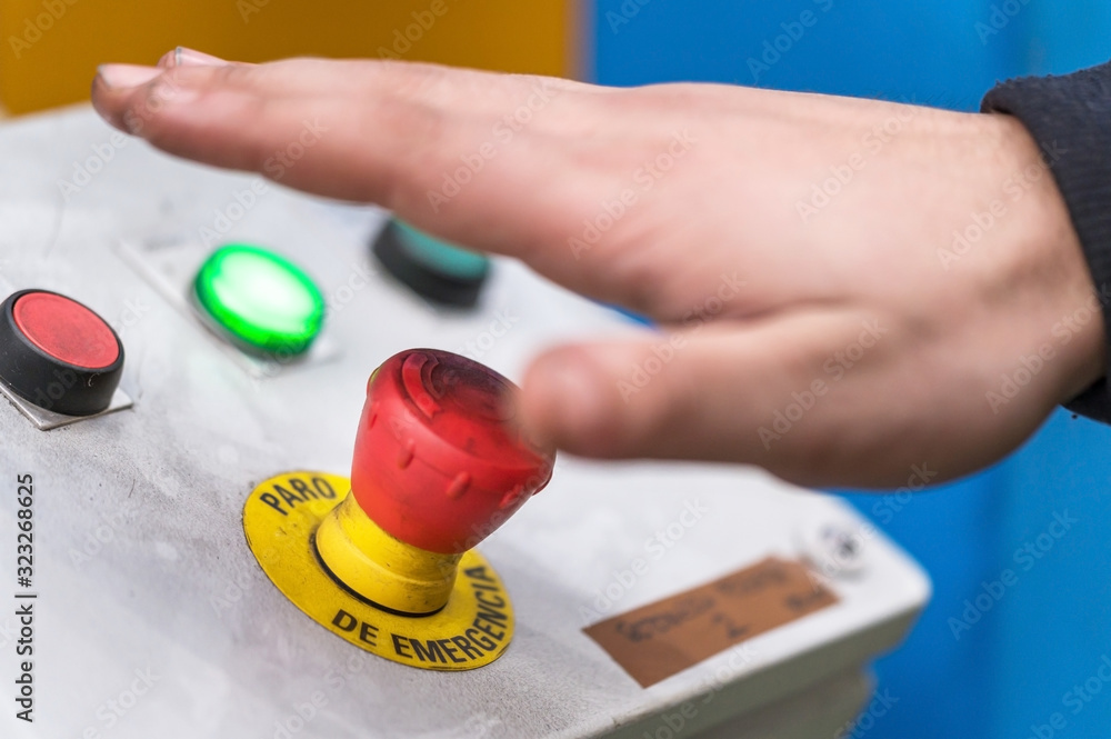 Hand pressing the red emergency button or stop button for industrial ...