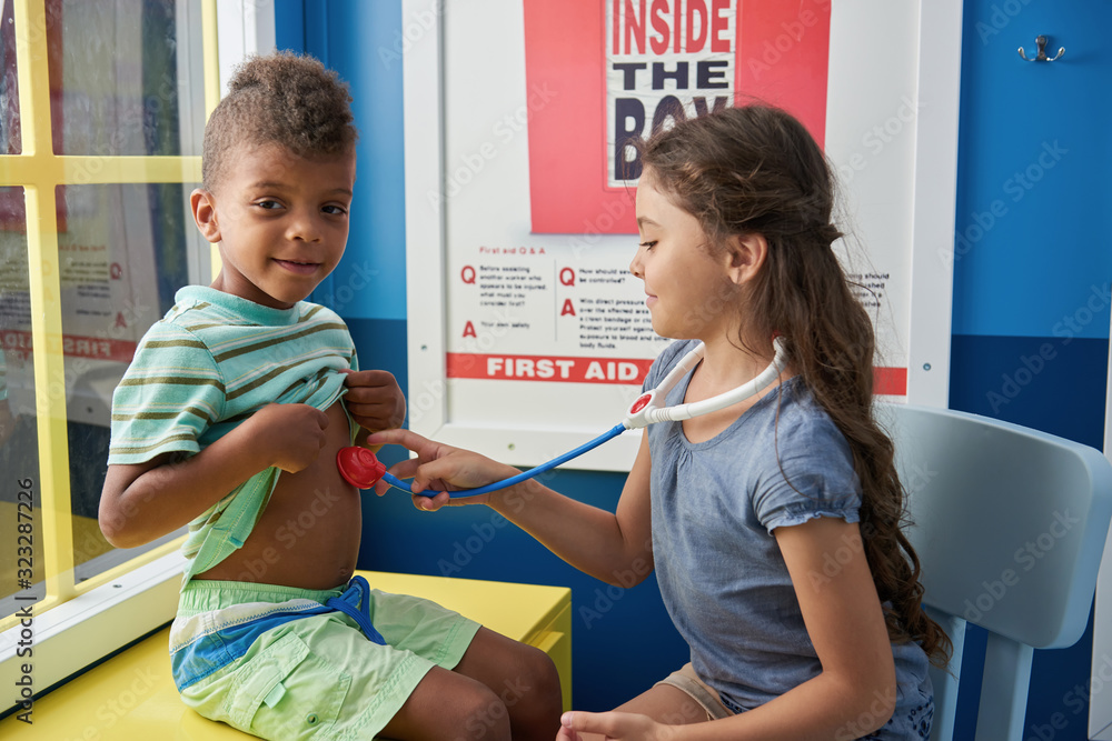 Two children playing doctor in playroom. Little girl doctor examining ...