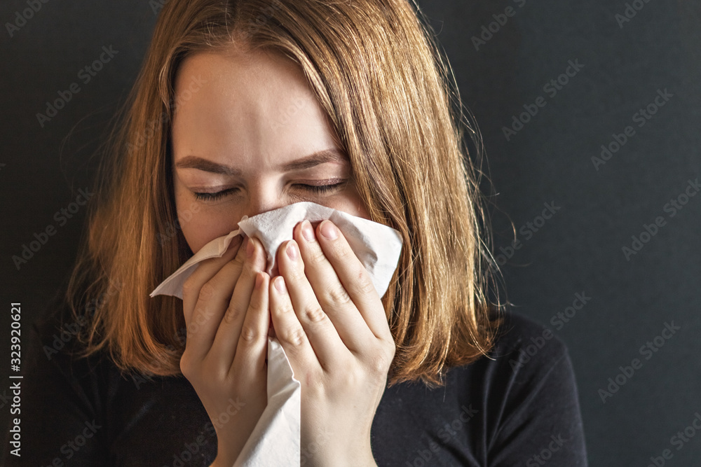 Sick young woman, with wrinkled nose, blowing her nose and fever ...
