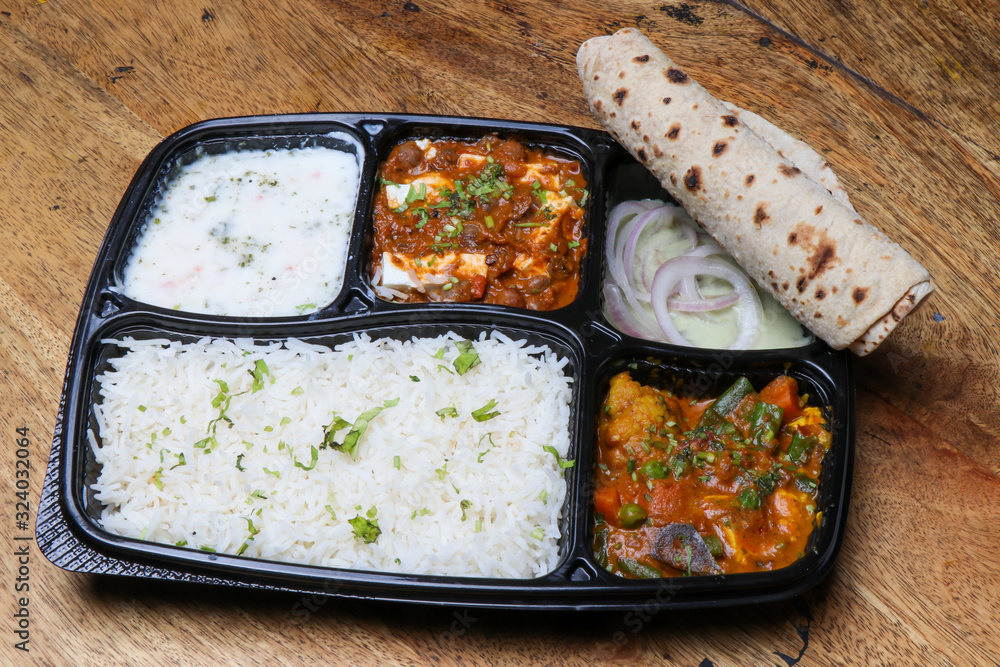 Indian food thali with rice chapati kadai paneer, mix vegetable, raita ...