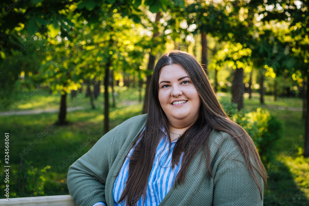 Beautiful and confident brunette smiling plus size model sitting in the ...