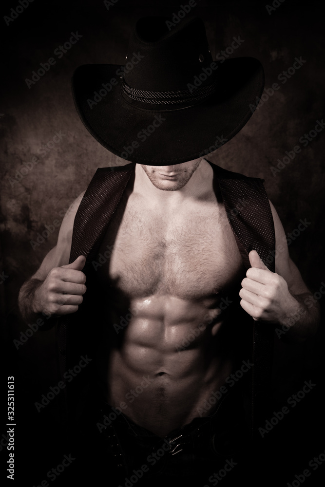 Attractive cowboy wearing hat covering his face opening waistcoat to ...
