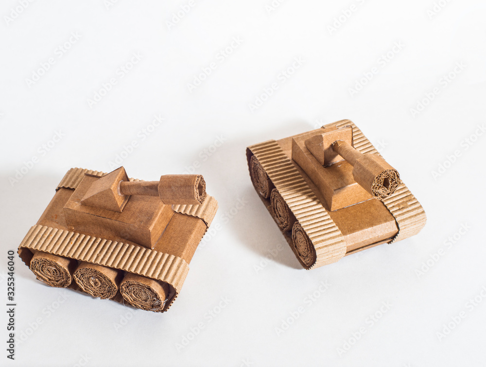 two toy tanks made by children from corrugated cardboard are fighting ...