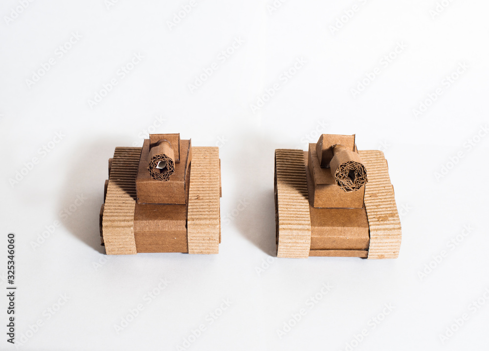 two toy tanks made by children from corrugated cardboard are fighting ...