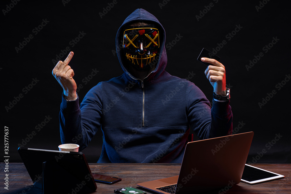 Foto de Stock dangerous anonymous hacker man in scary mask sit at table with laptop, aggressive ...