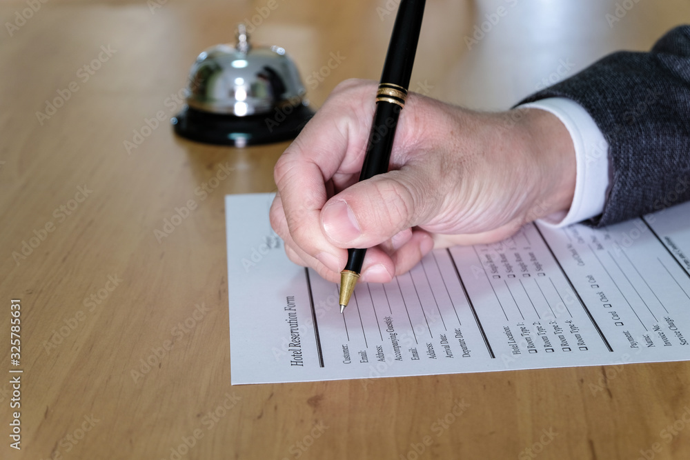 Men business person use pen to writing on a hotel reservation form at ...