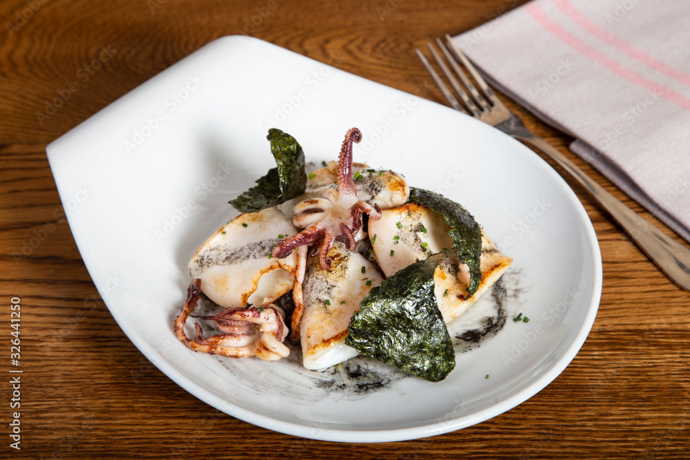 Grilled squid dish with sauteed black sausage, candied onion and crispy ...