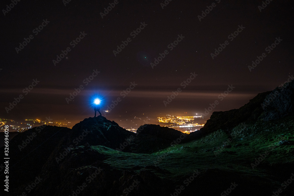 Silhouette of a young man with a blue light on Mount Aiako Harria in ...
