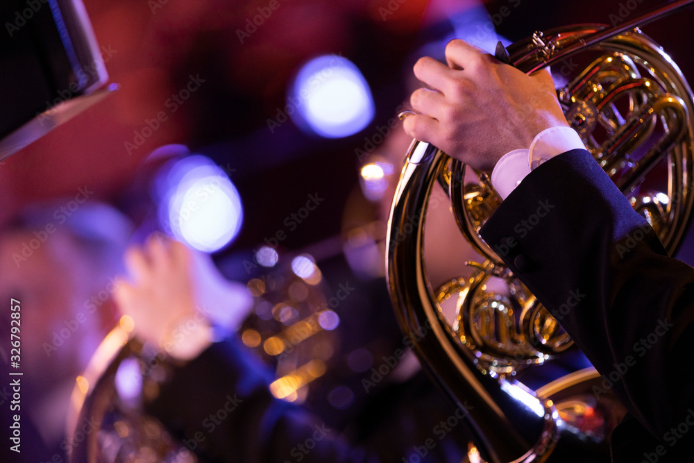 A French horn player playing his instrument in a classical symphony ...