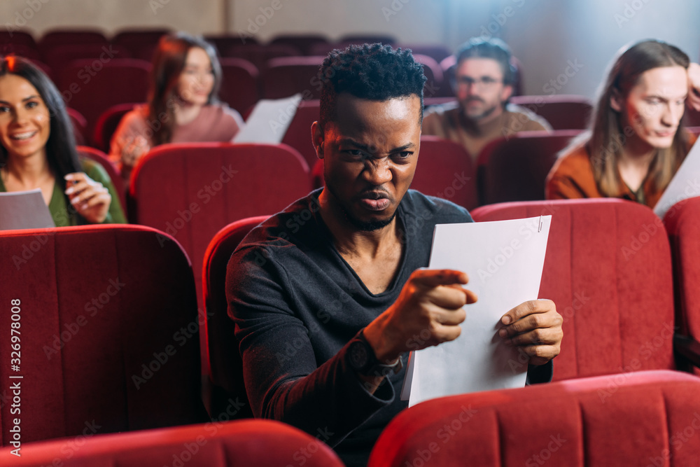 angry african american actor rehearsing on red chairs with actors Stock ...