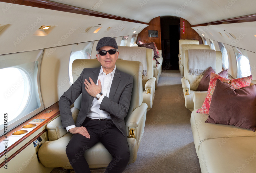 Handsome man sitting inside a private jet alone. Stock Photo | Adobe Stock