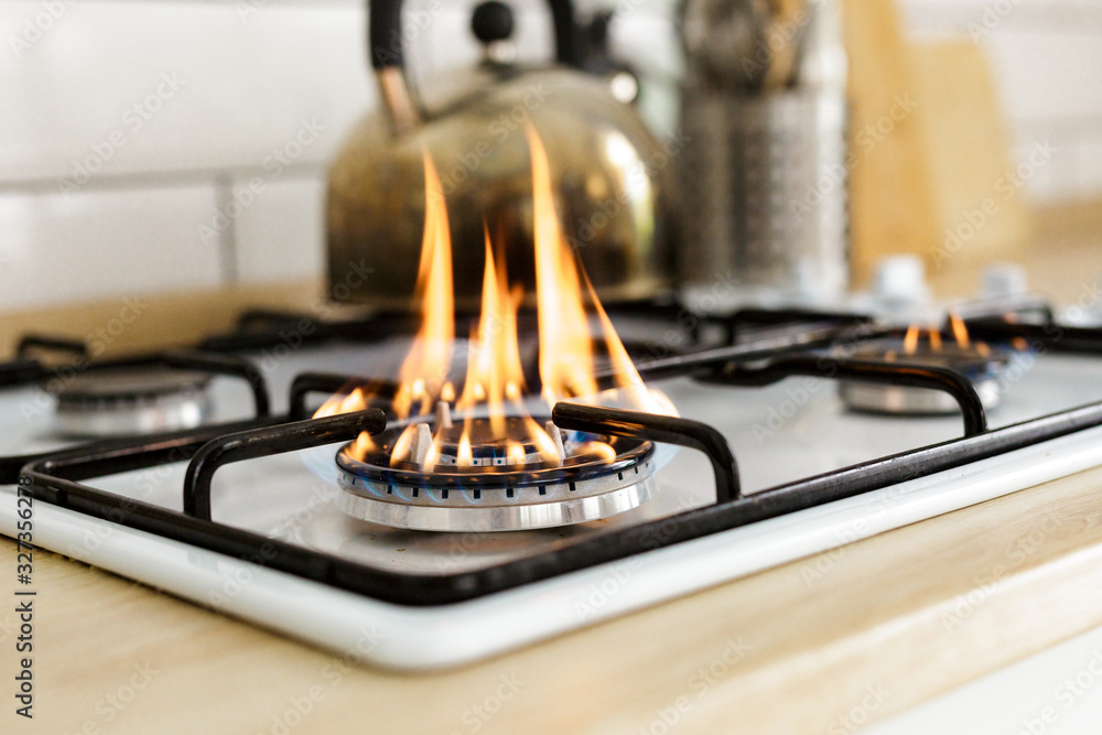Macro closeup of modern luxury gas stove top with blue fire flame knobs ...
